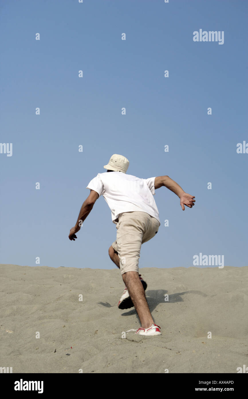 Rear view of a man running on sand in a desert Stock Photo - Alamy