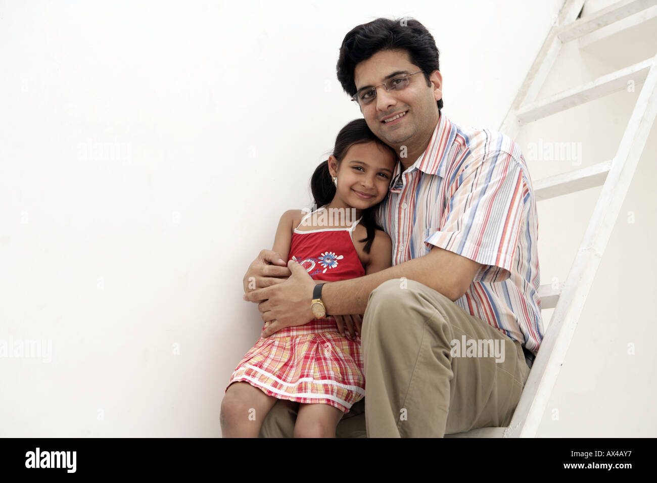 Father sitting with his daughter on a ladder and smiling Stock Photo ...