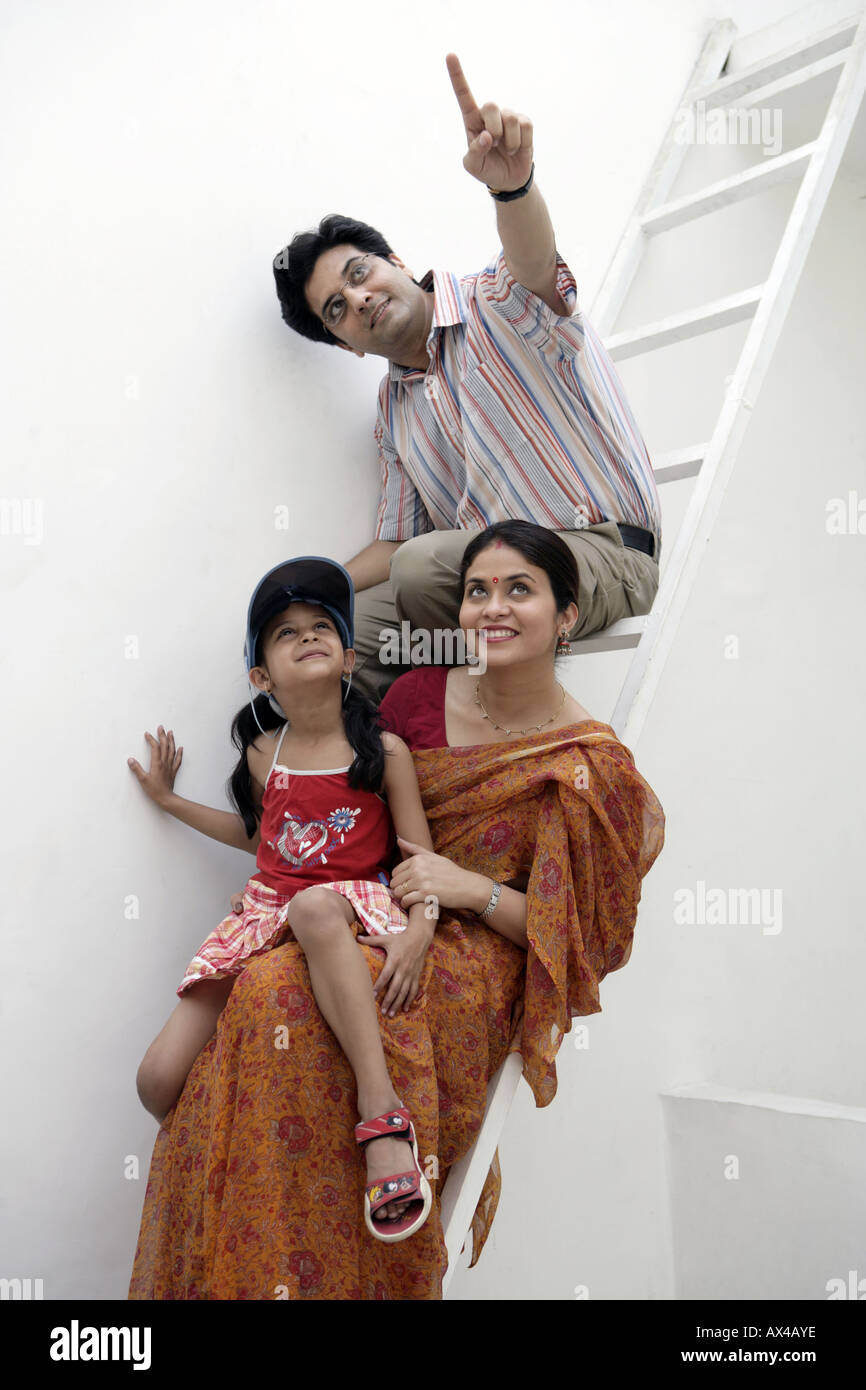 Man sitting with his family on a ladder and pointing Stock Photo - Alamy