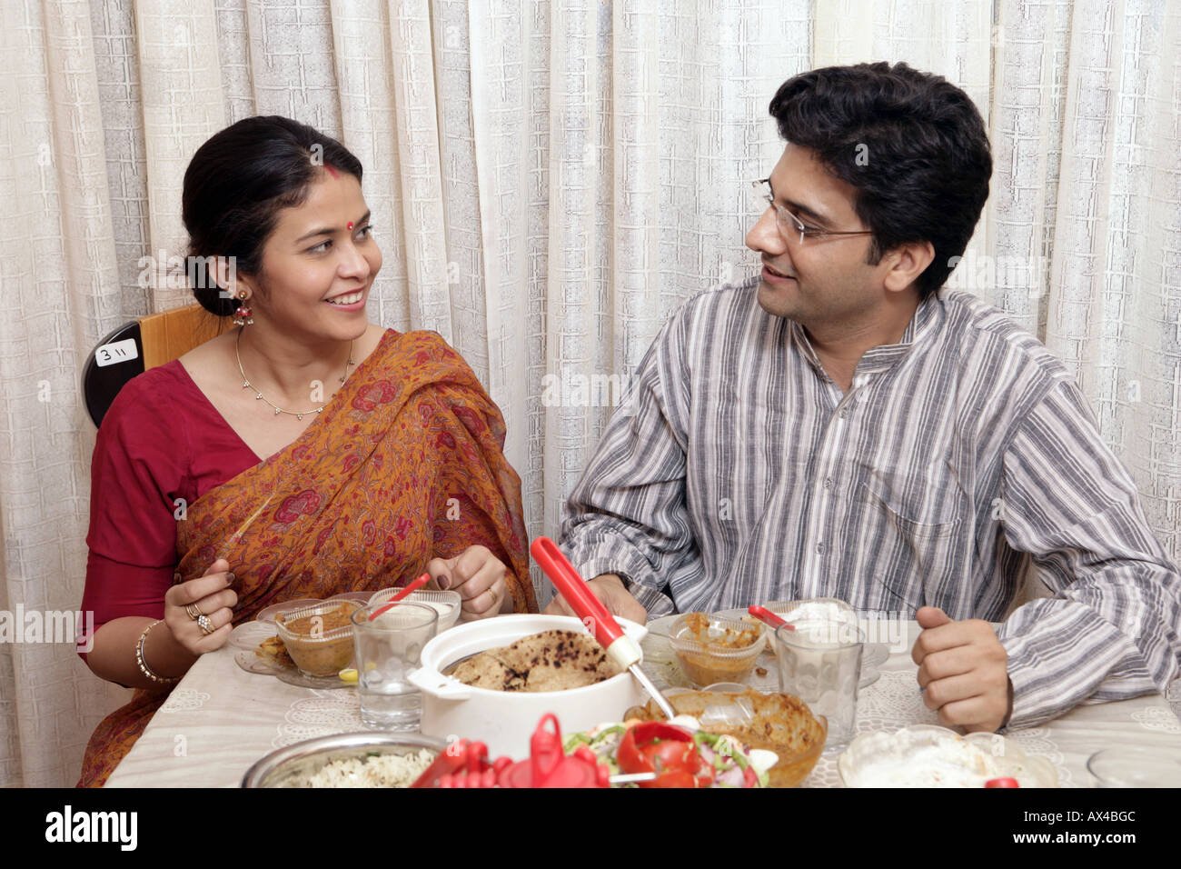 Couple eating at dining table and smiling Stock Photo - Alamy