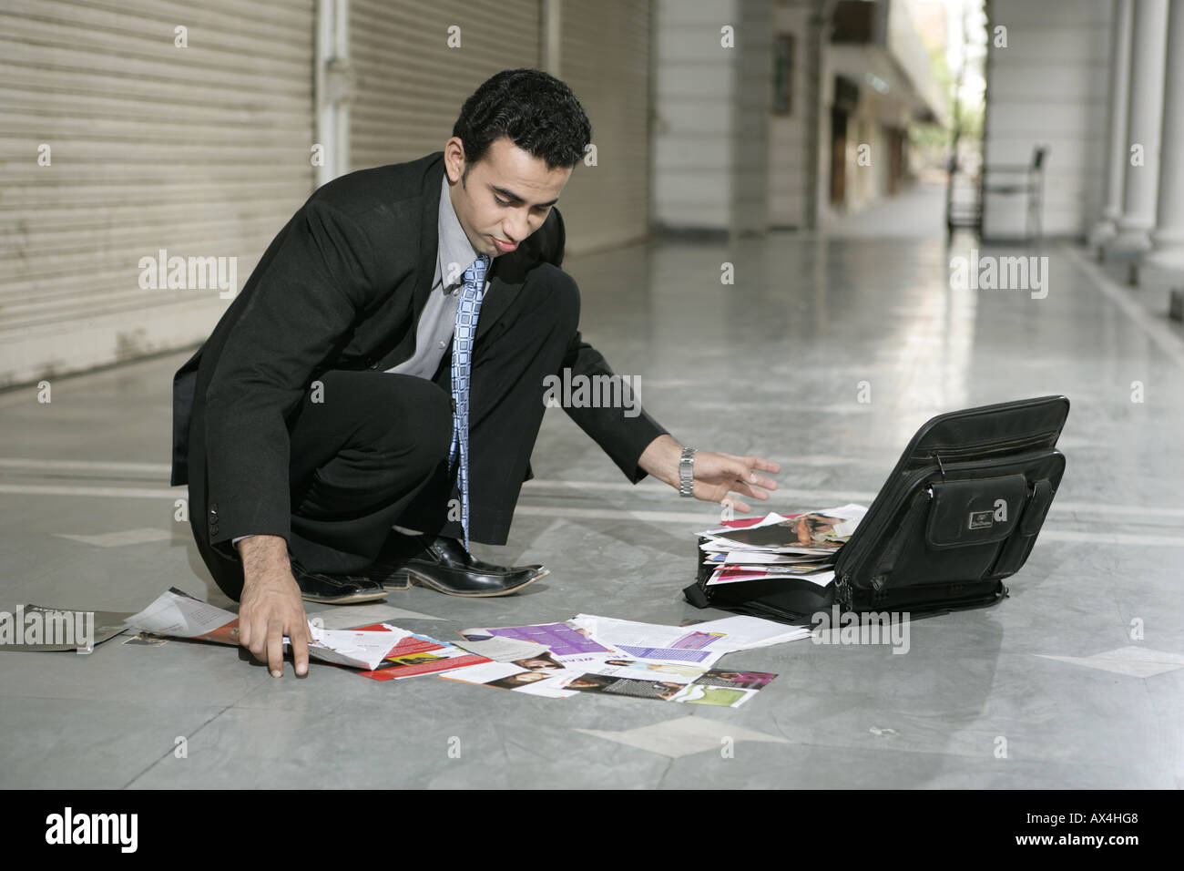 Businessman gathering his fallen papers from the floor Stock Photo - Alamy