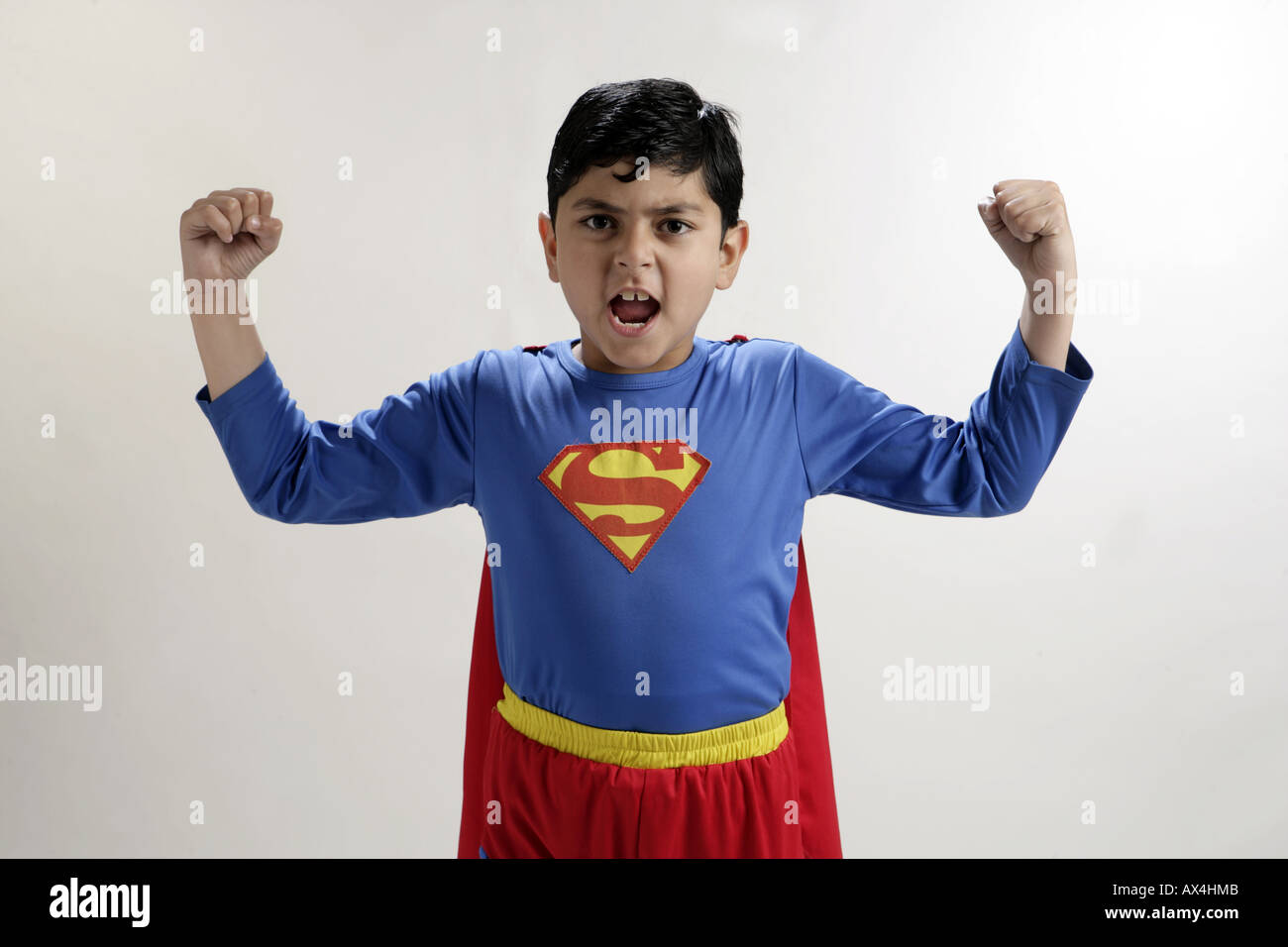 Portrait of a boy wearing superman costume and flexing his muscles ...