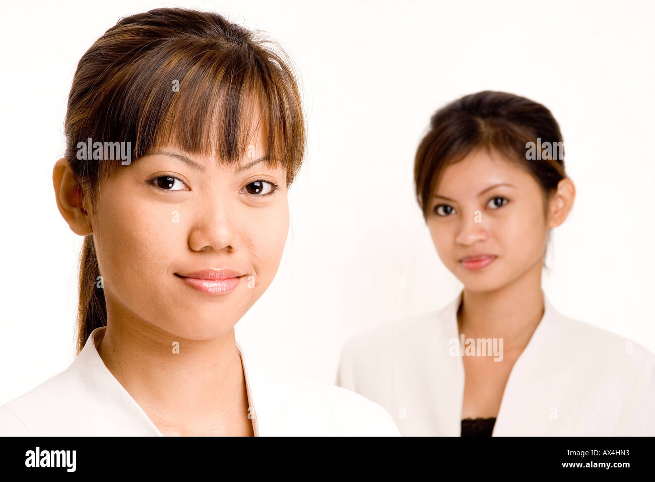 Two cute asian women in matching suits on white background Stock Photo ...