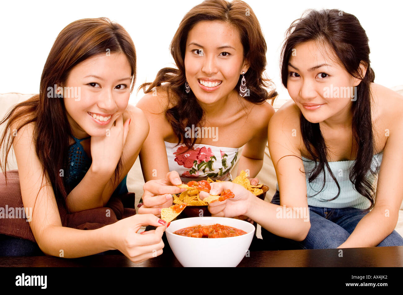 Three pretty asian women eating nachos and salsa dip Stock Photo - Alamy