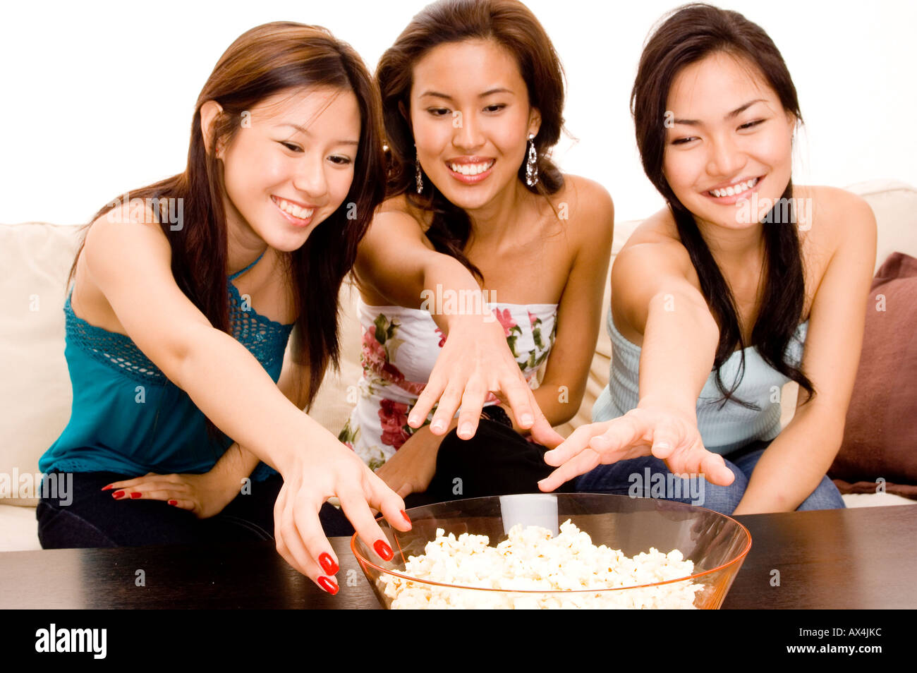 Three attractive asian women reach for popcorn Stock Photo - Alamy