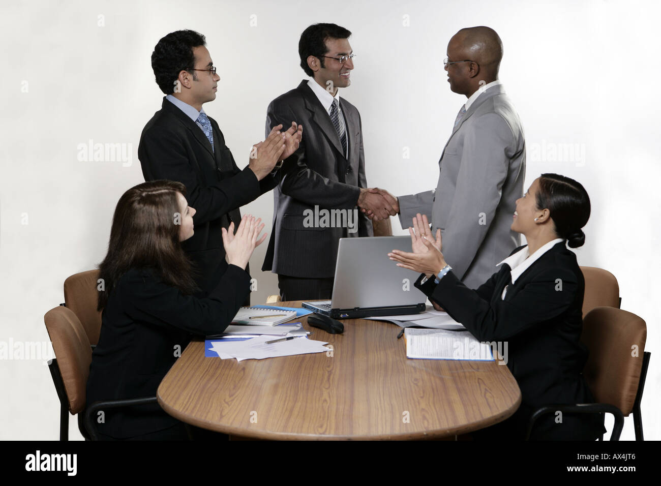 Two business partners shaking hands in a boardroom with their employee ...