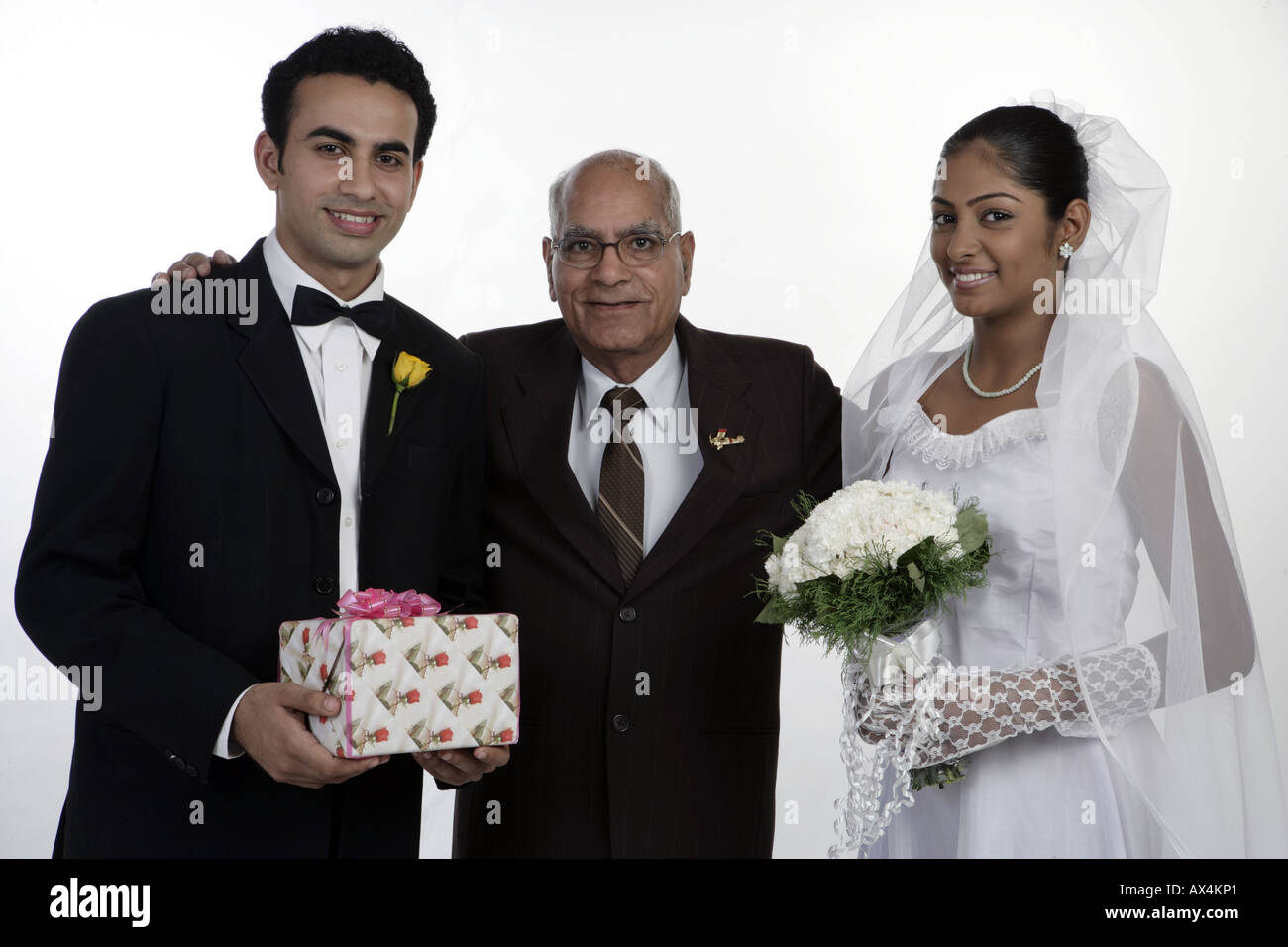 Portrait of a groom and a bride standing with their father and smiling ...