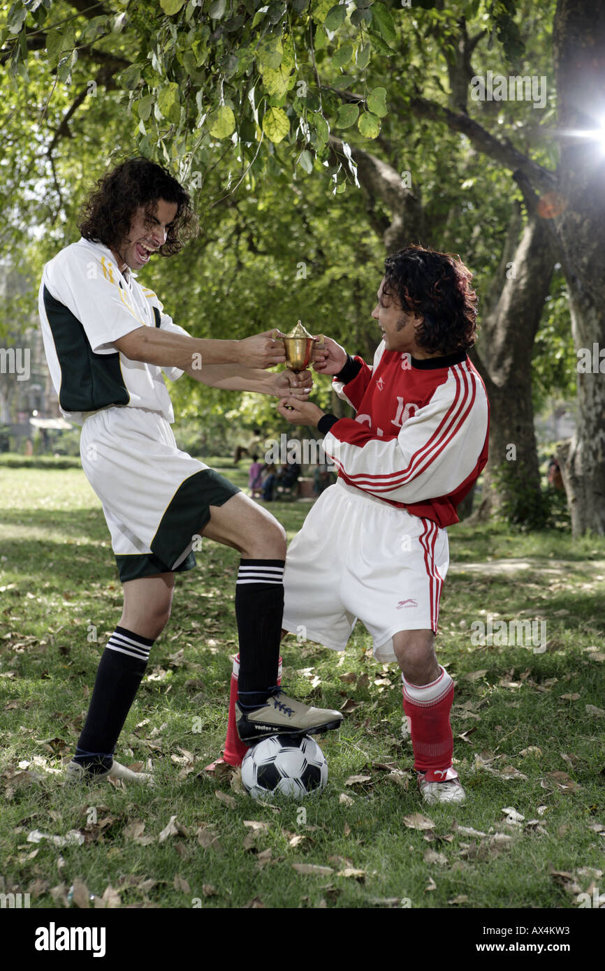 Side profile of a two football players snatching a victory cup in a ...