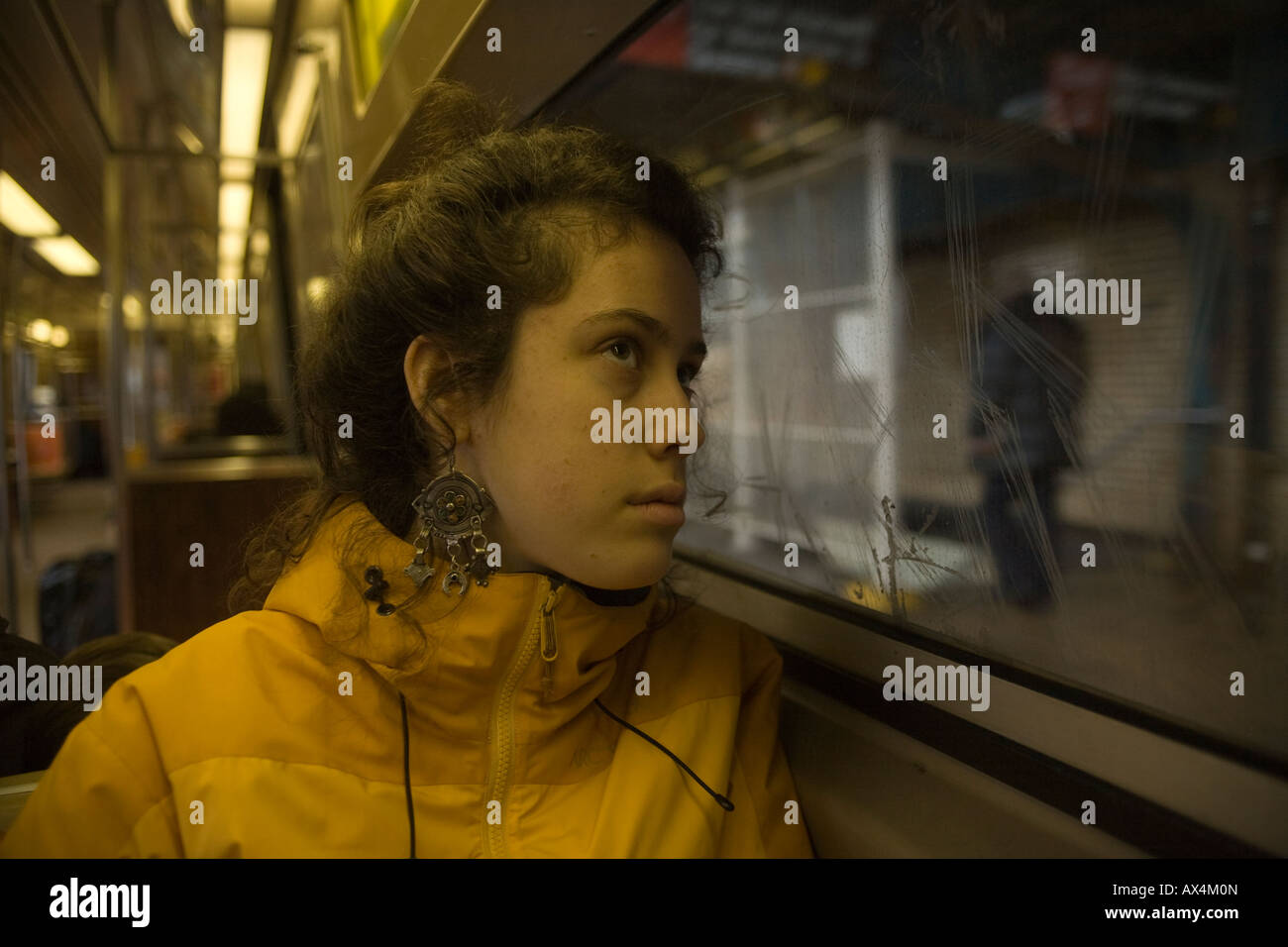 Young woman looks out subway window in an above ground station in ...