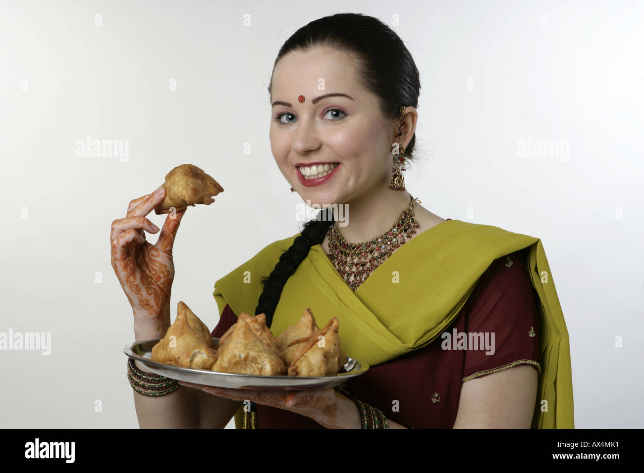Portrait of a young woman eating samosa and smiling Stock Photo - Alamy