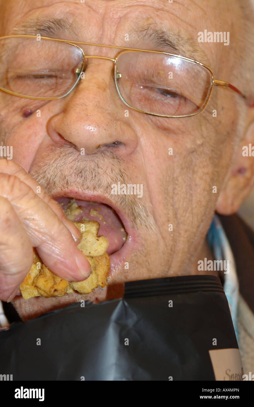 Elderly man eating a packet of crisps Newport South Wales GB UK 2008 ...