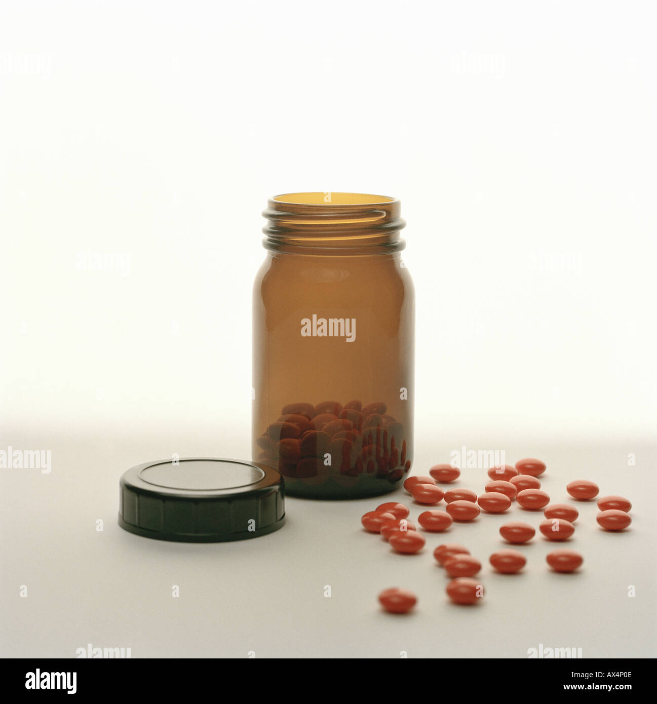 Red pills with open pill bottle Stock Photo - Alamy