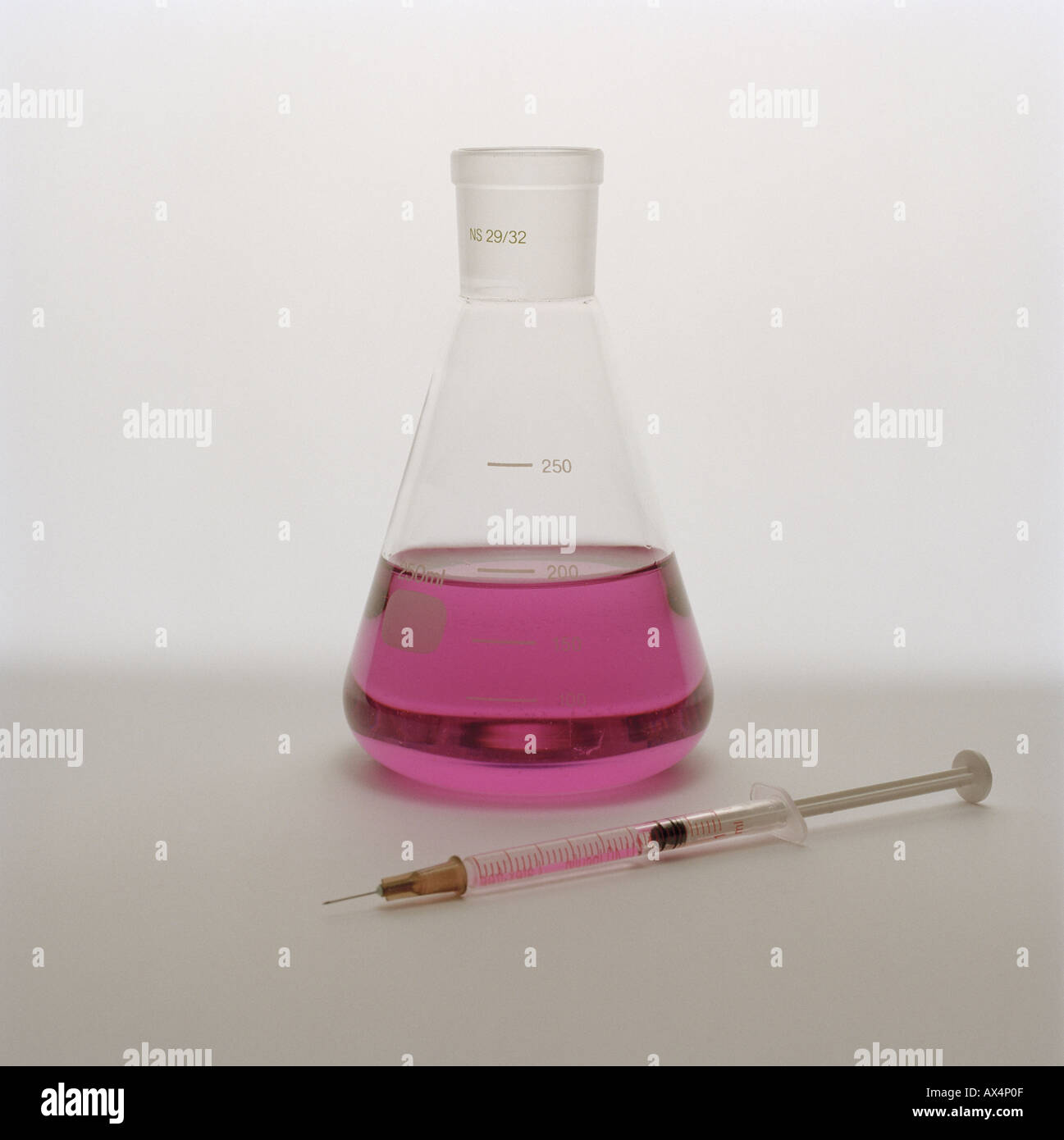 Syringe and beaker containing pink liquid Stock Photo - Alamy
