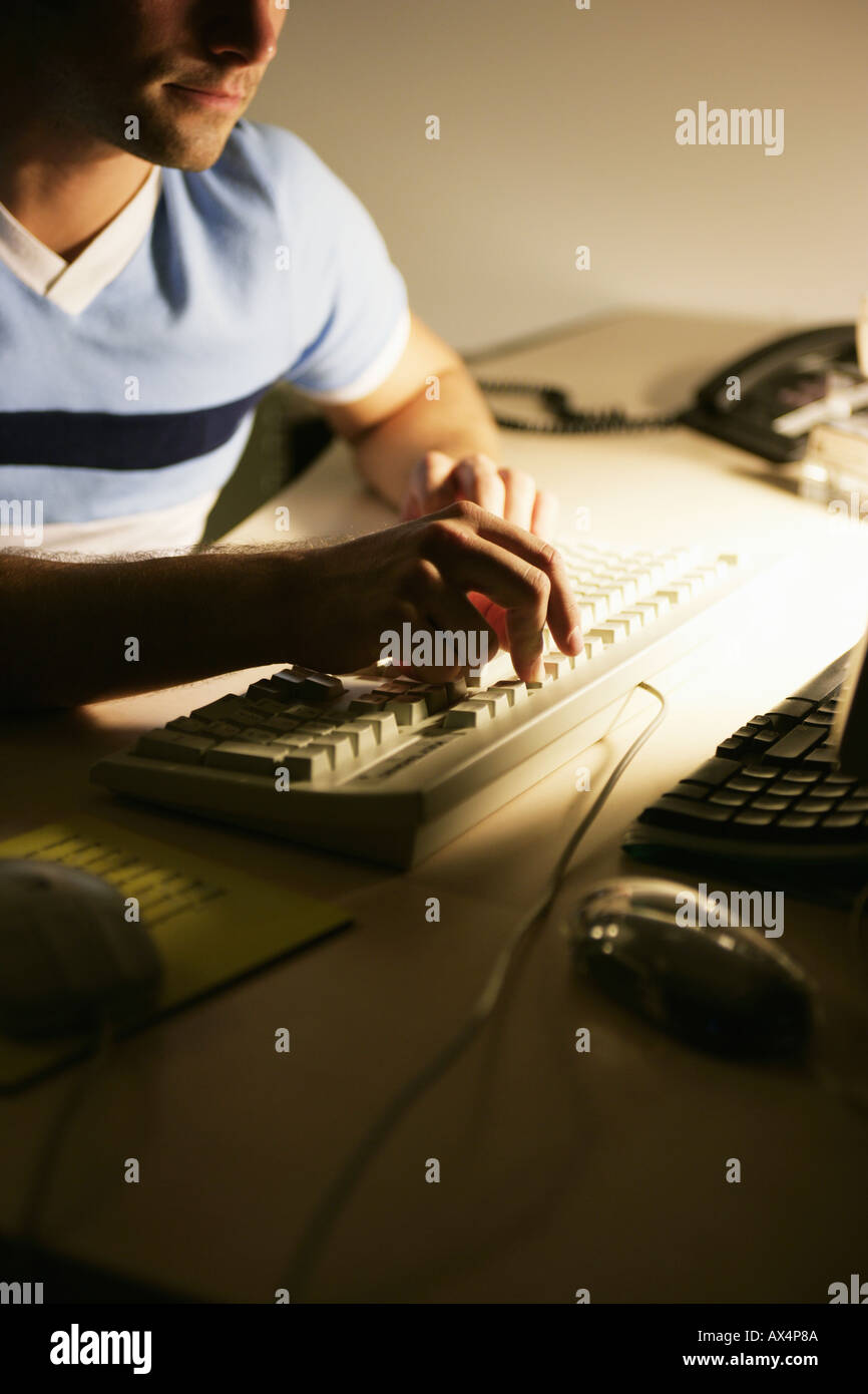 Man sitting at an office desk typing Stock Photo - Alamy