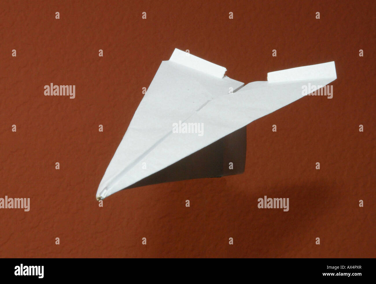 White paper airplane flies though air against brown background Stock ...