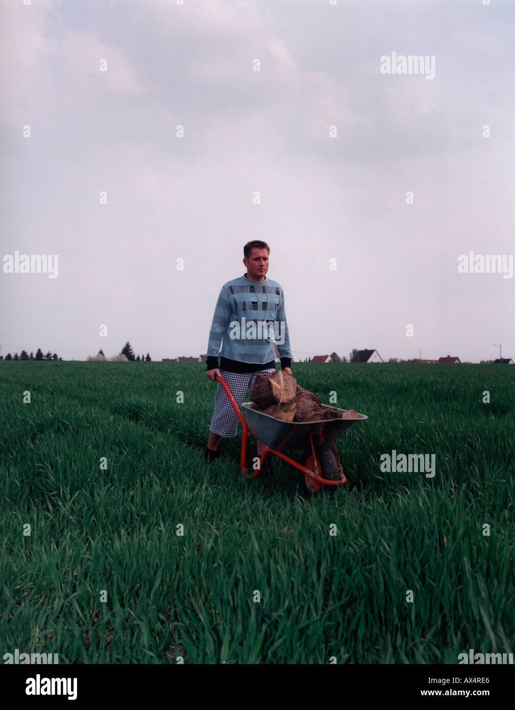 Man pushing wheelbarrow Stock Photo - Alamy
