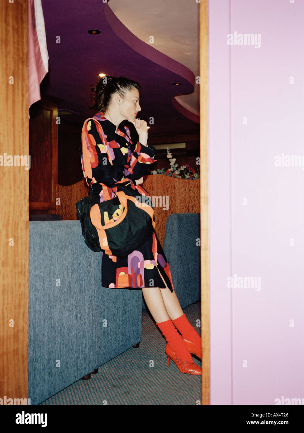 Woman leaning against couch Stock Photo - Alamy