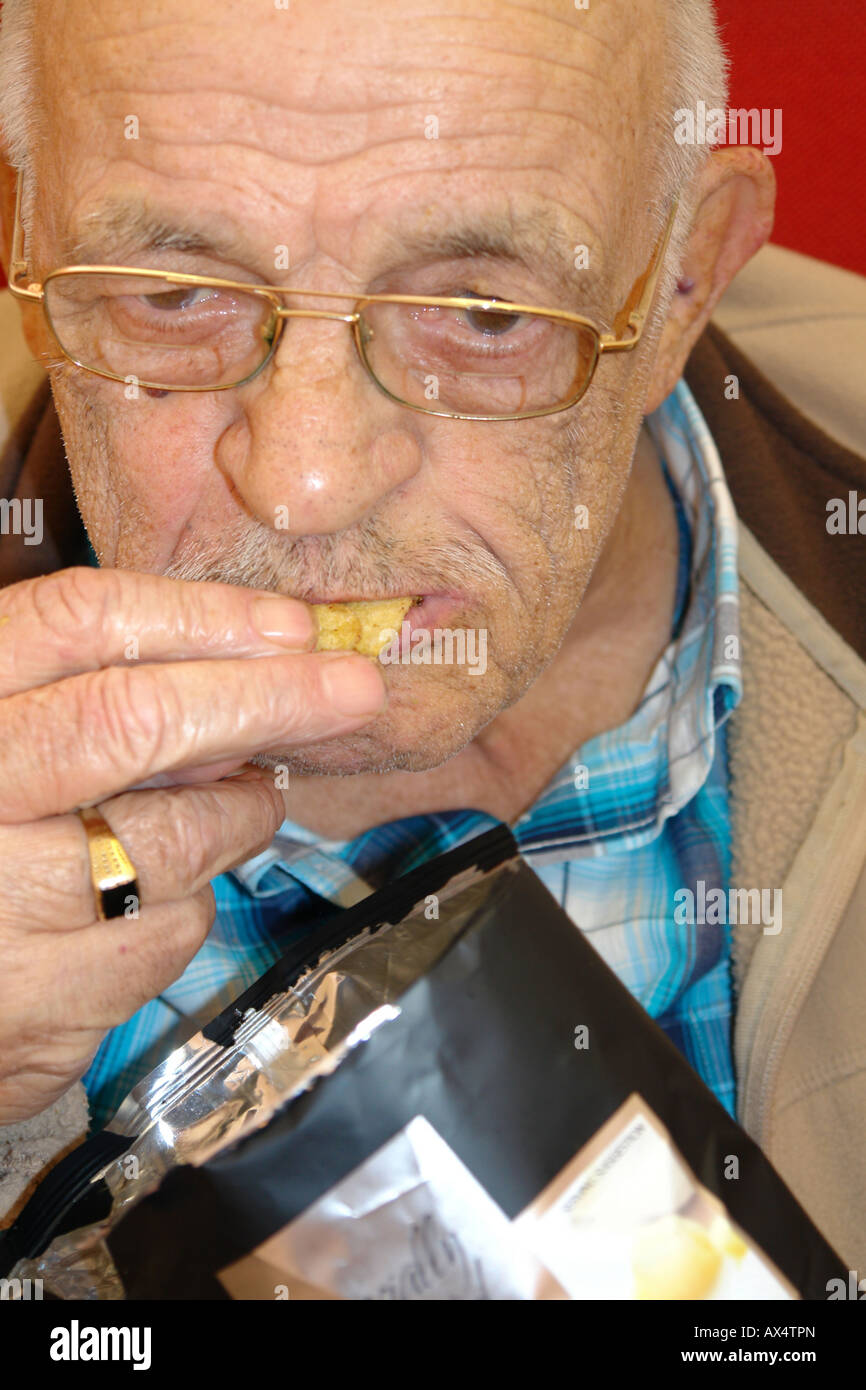 Elderly man eating a packet of crisps Newport South Wales GB UK 2008 ...