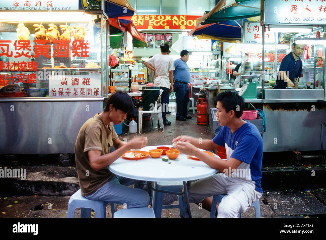 Two Malaysian men eating at a roadside restaurant in Kuala Lumpur, the ...