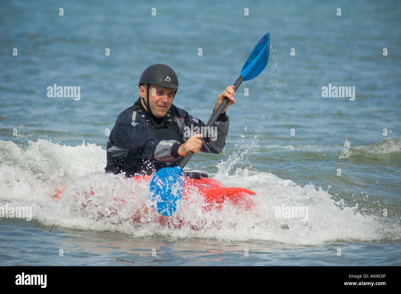 Mature male caucasian kayaker in the sea surfing waves at Cayton Bay ...