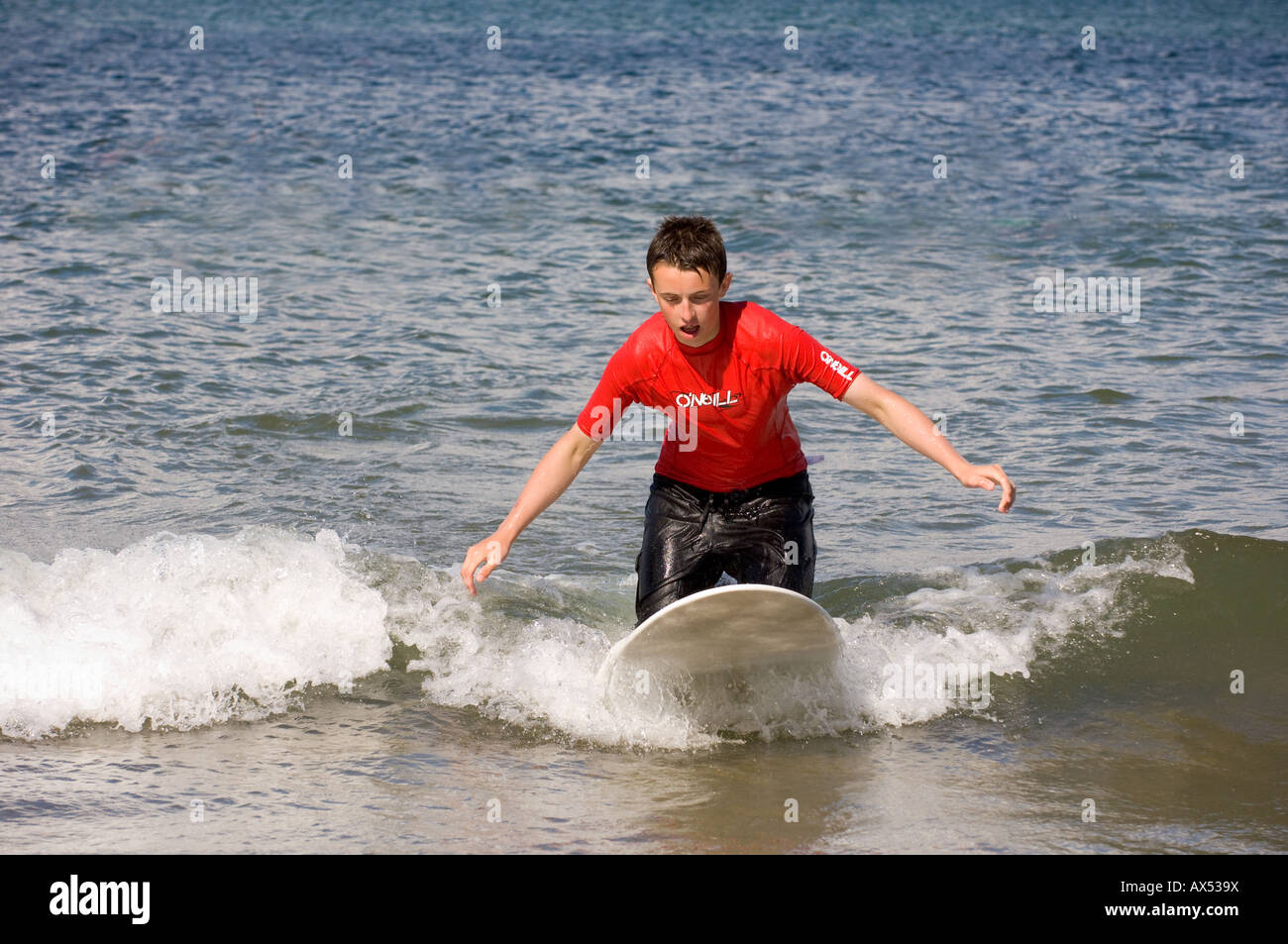 Teenage boy attempting to stand up on a surf board whilst learning to ...