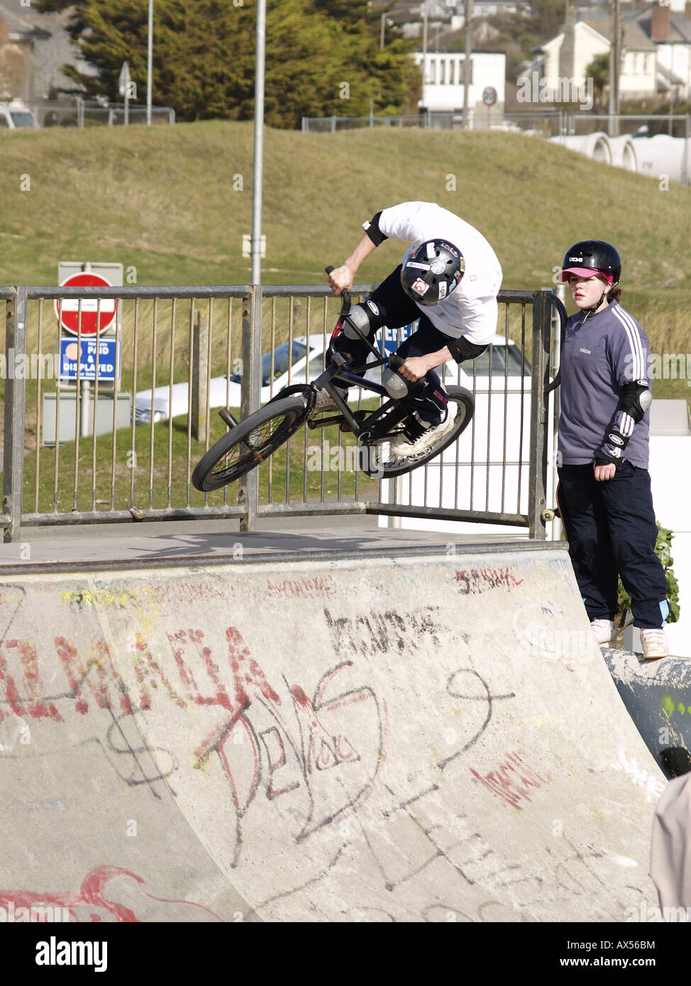 Teenage BMX rider on half pipe in skate park , wearing safety helmet ...