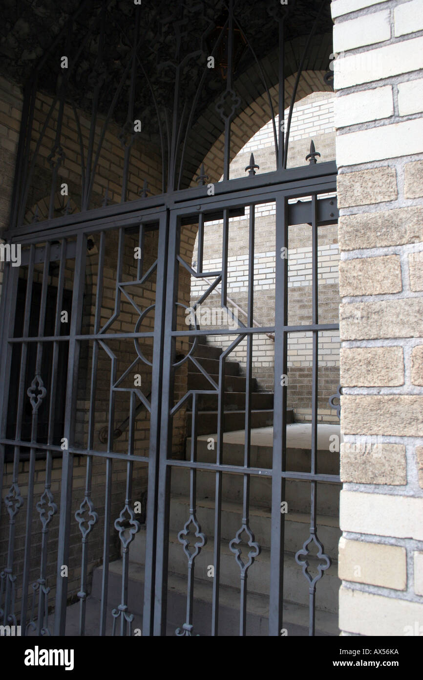 A metal gate in a brick wall with different colored bricks and stairs ...