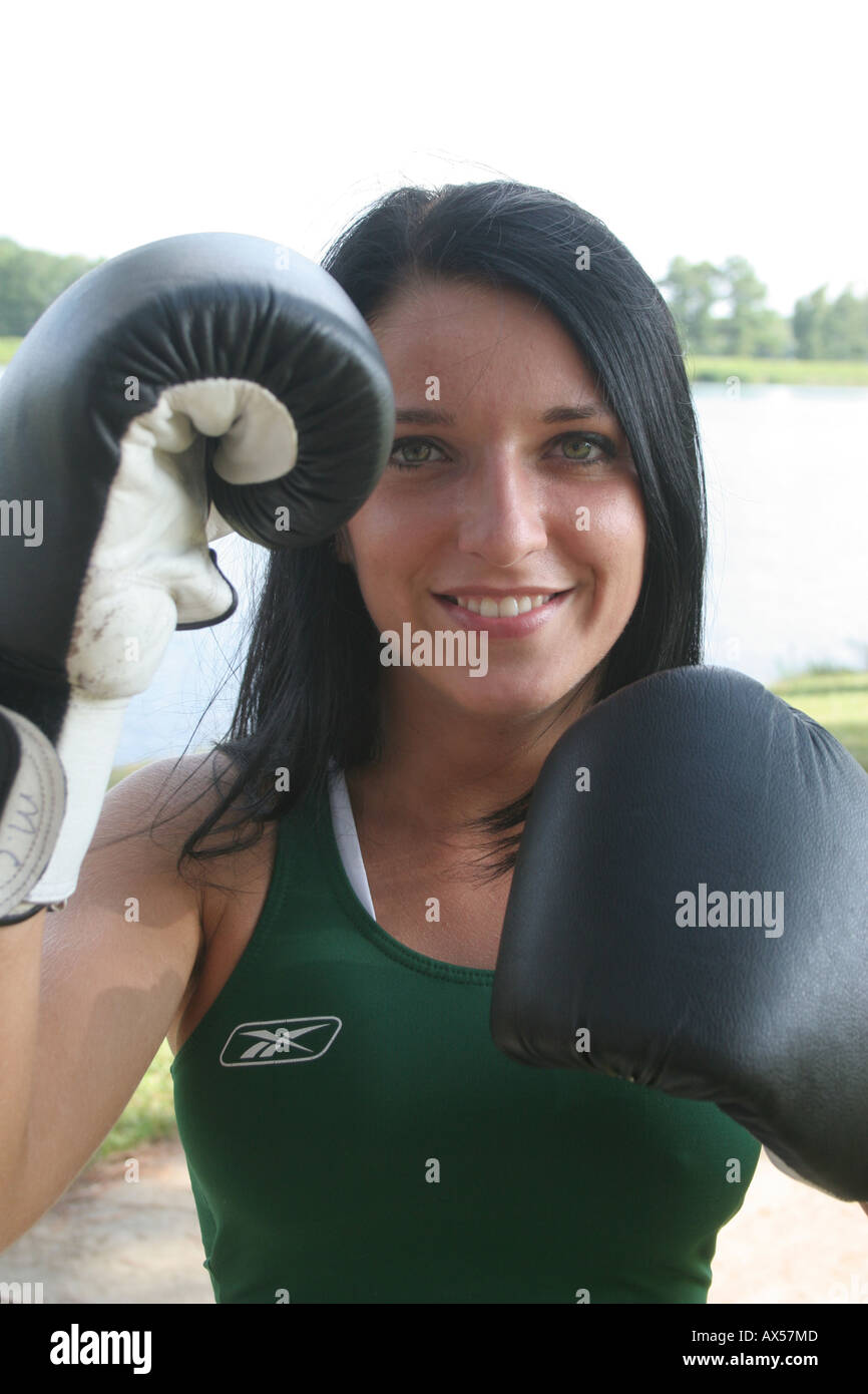 A caucasian woman outside with boxing gloves and posed to hit the ...