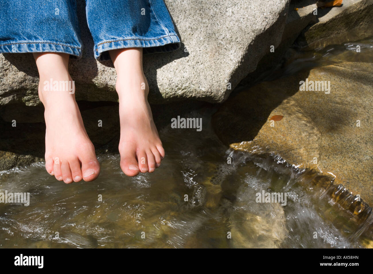 A child's feet dangling over cool water on a hot day in the city Stock ...