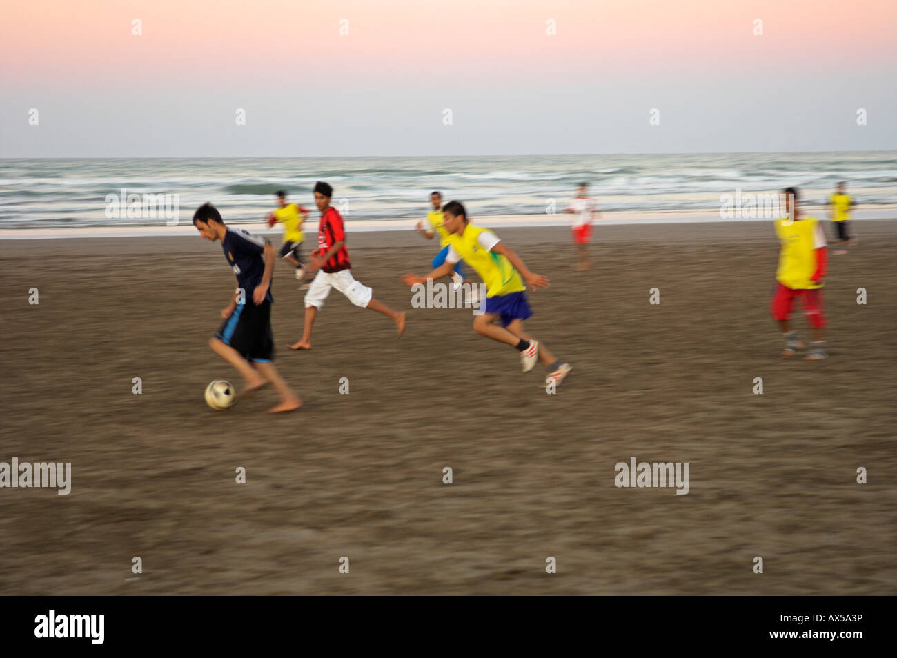 Playing football on the beach at dusk Stock Photo - Alamy
