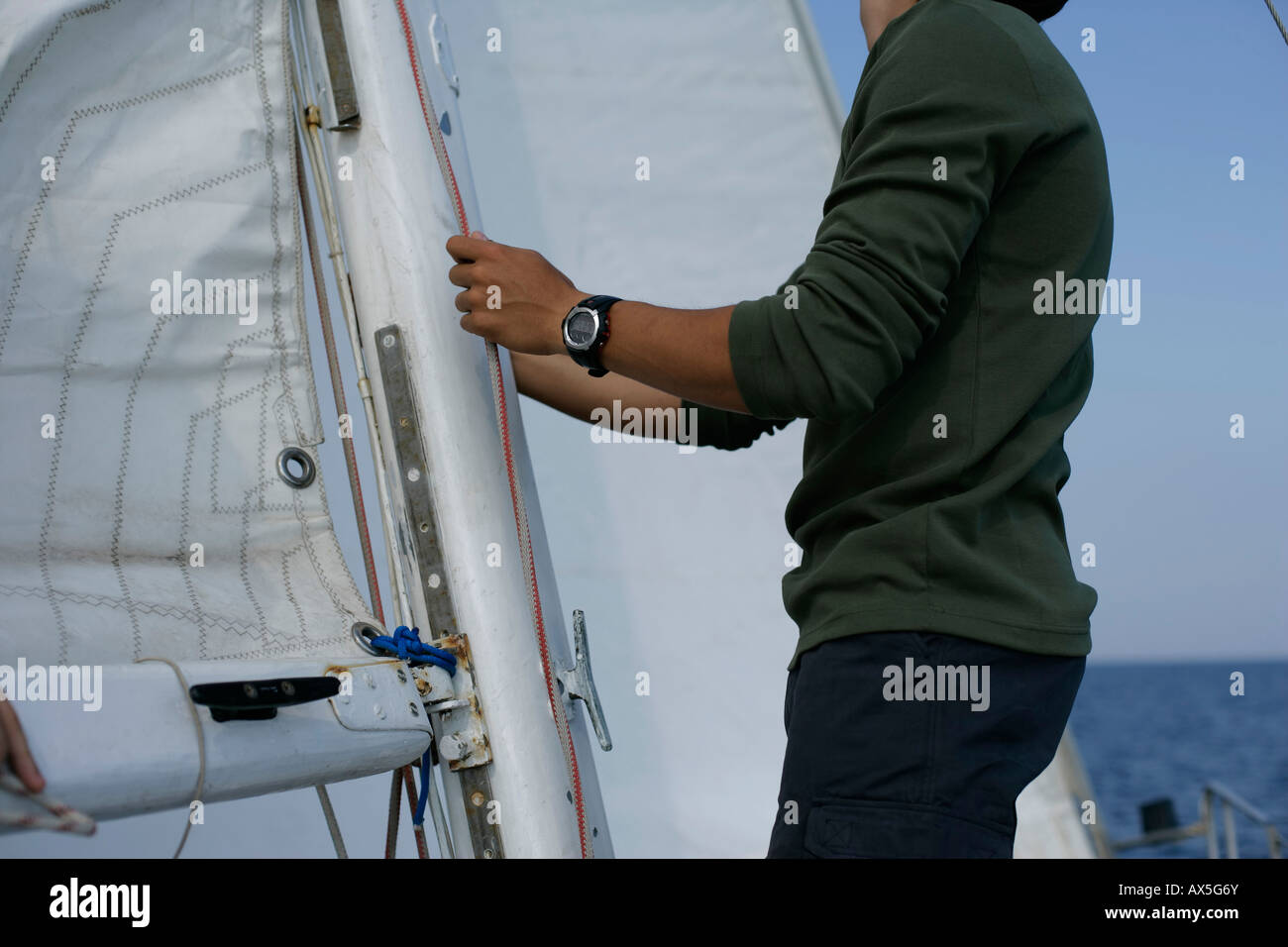 Man hoisting a sail Stock Photo - Alamy
