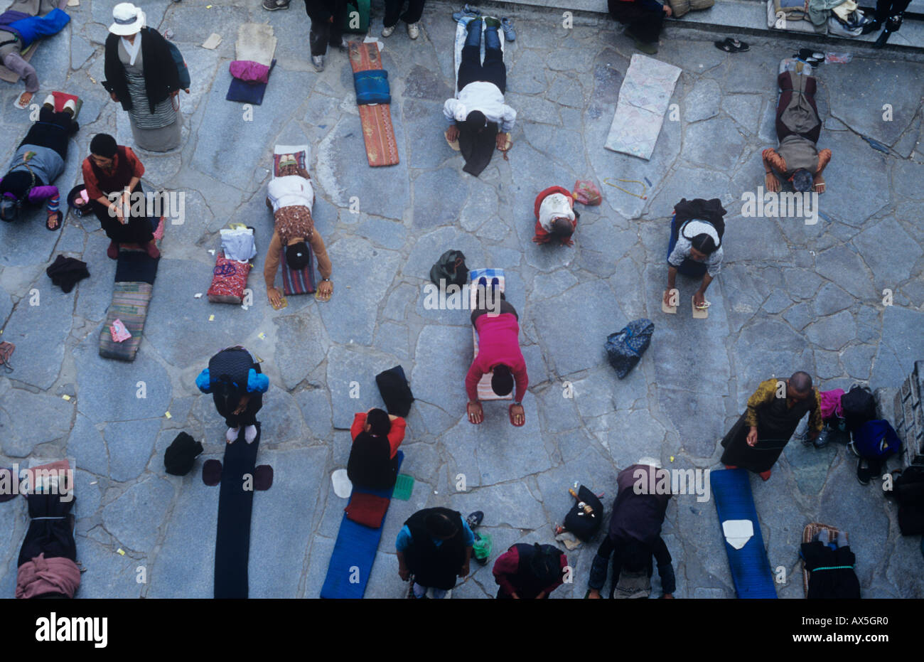 Buddhist pilgrims prostrate in front of the Jokhang Temple in Lhasa ...
