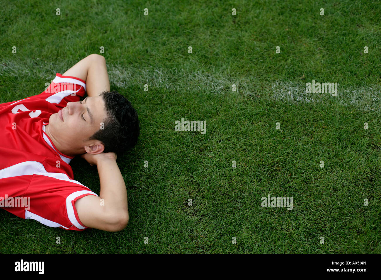 Soccer player with closed eyes lying on grass Stock Photo - Alamy