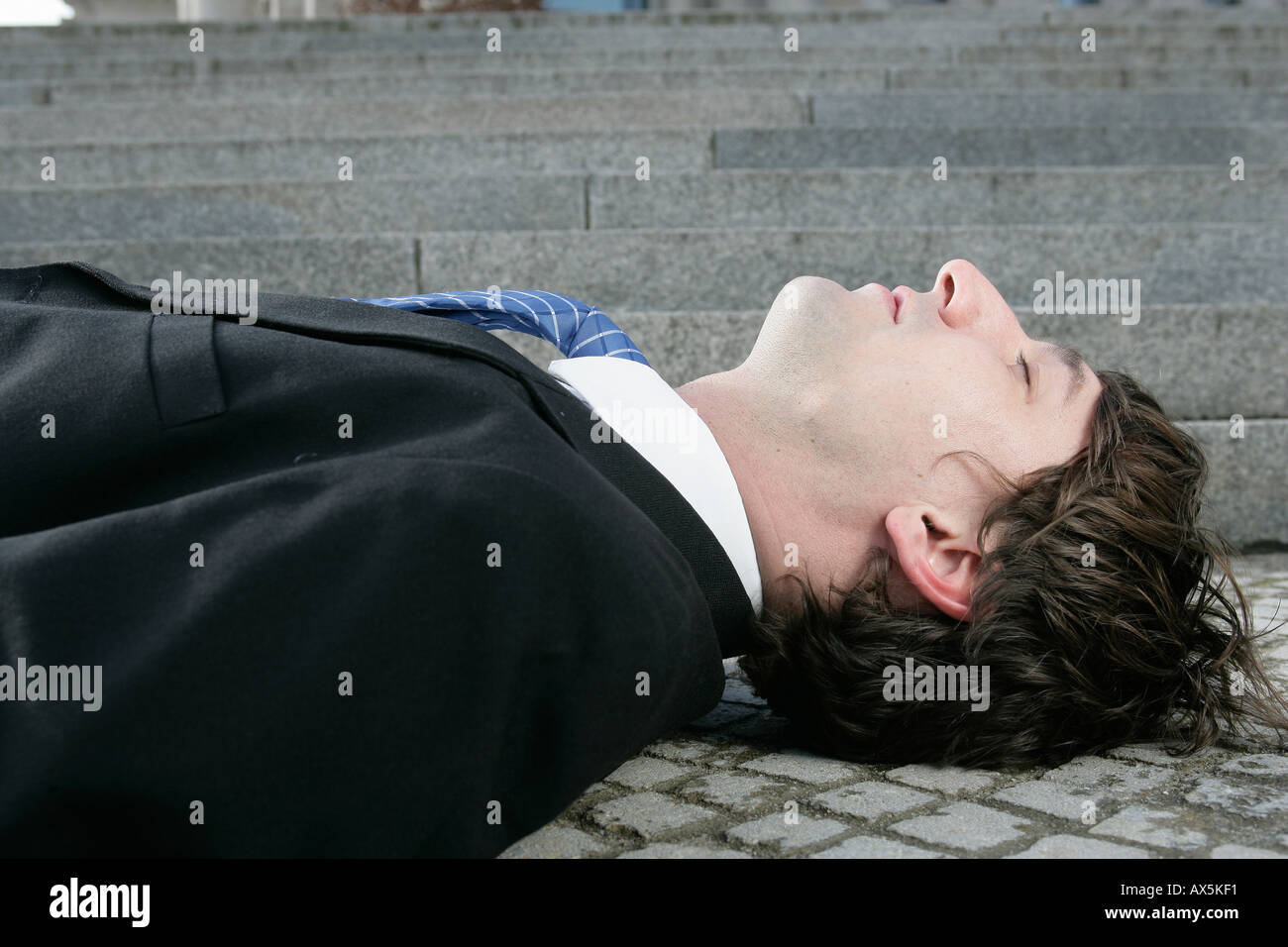 A businessman lying down in front of steps Stock Photo - Alamy