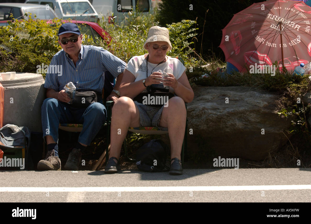 Cycling fans wait by the roadside for the tour de france racers to ...