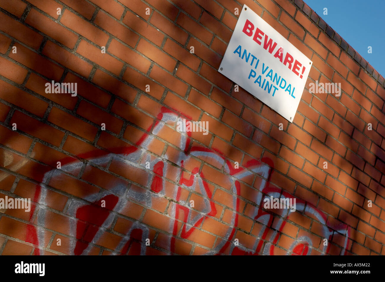 Beware Anti Vandal Paint sign on a graffitied brick wall Stock Photo ...