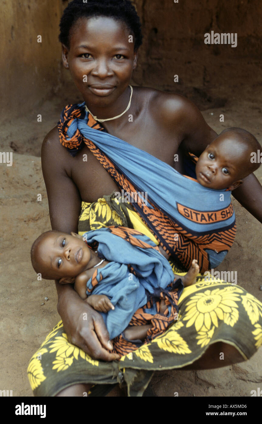 Kisamba, Tanzania. Mother with twin babies, one slung round her, the ...
