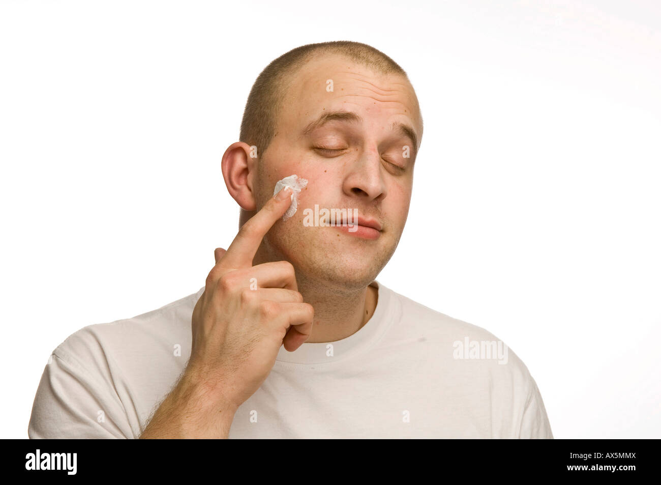 Young man applying lotion to his face Stock Photo - Alamy