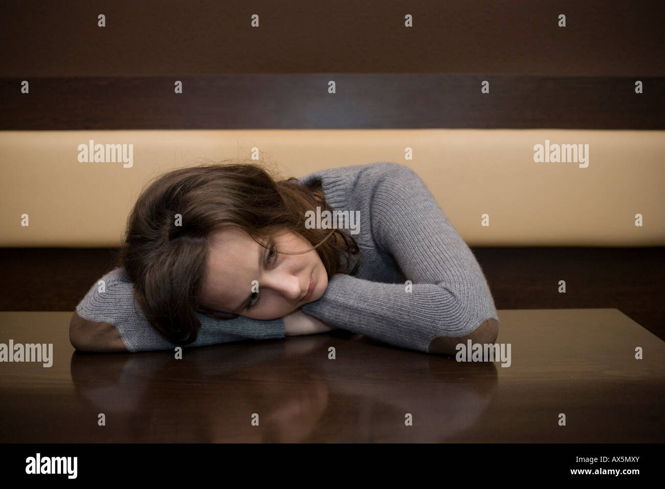 Young woman leaned over the table at a bar, looking depressed Stock ...