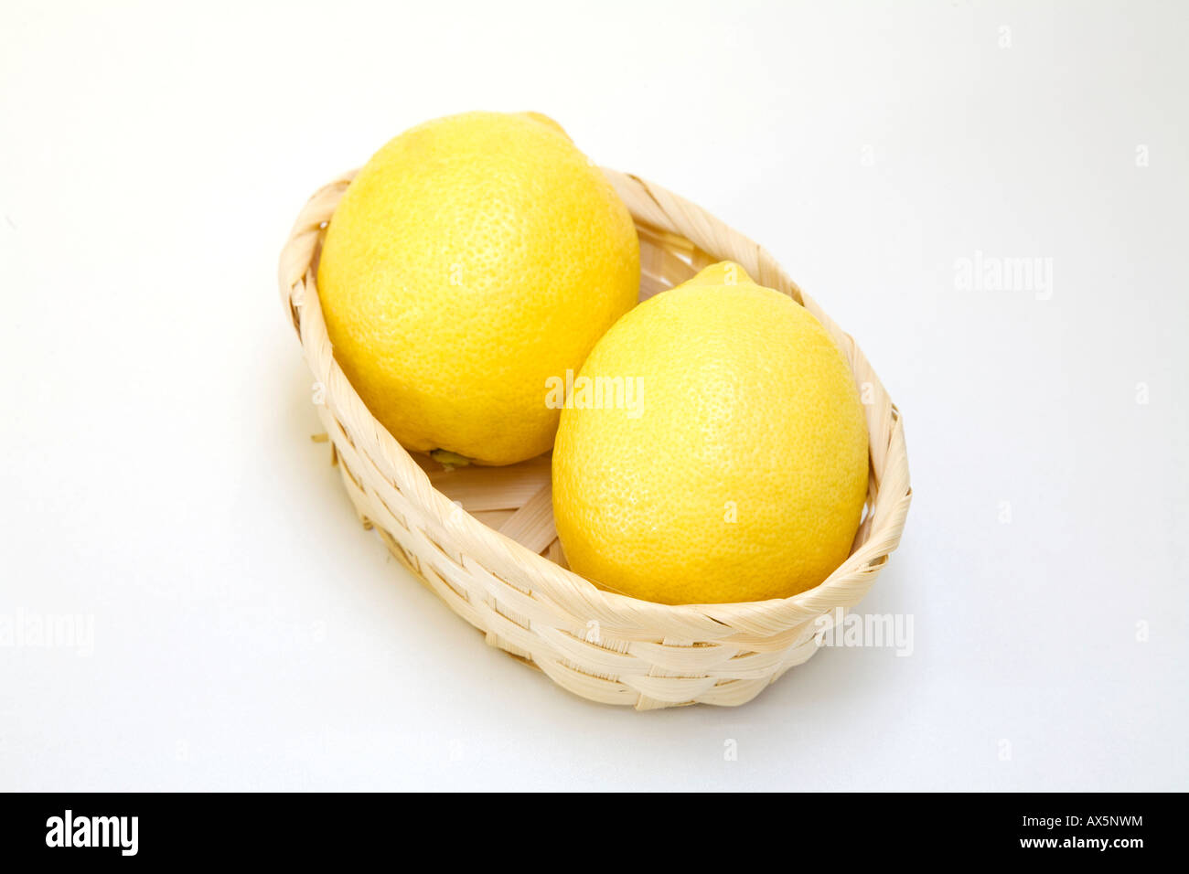 Two lemons in a small basket Stock Photo - Alamy