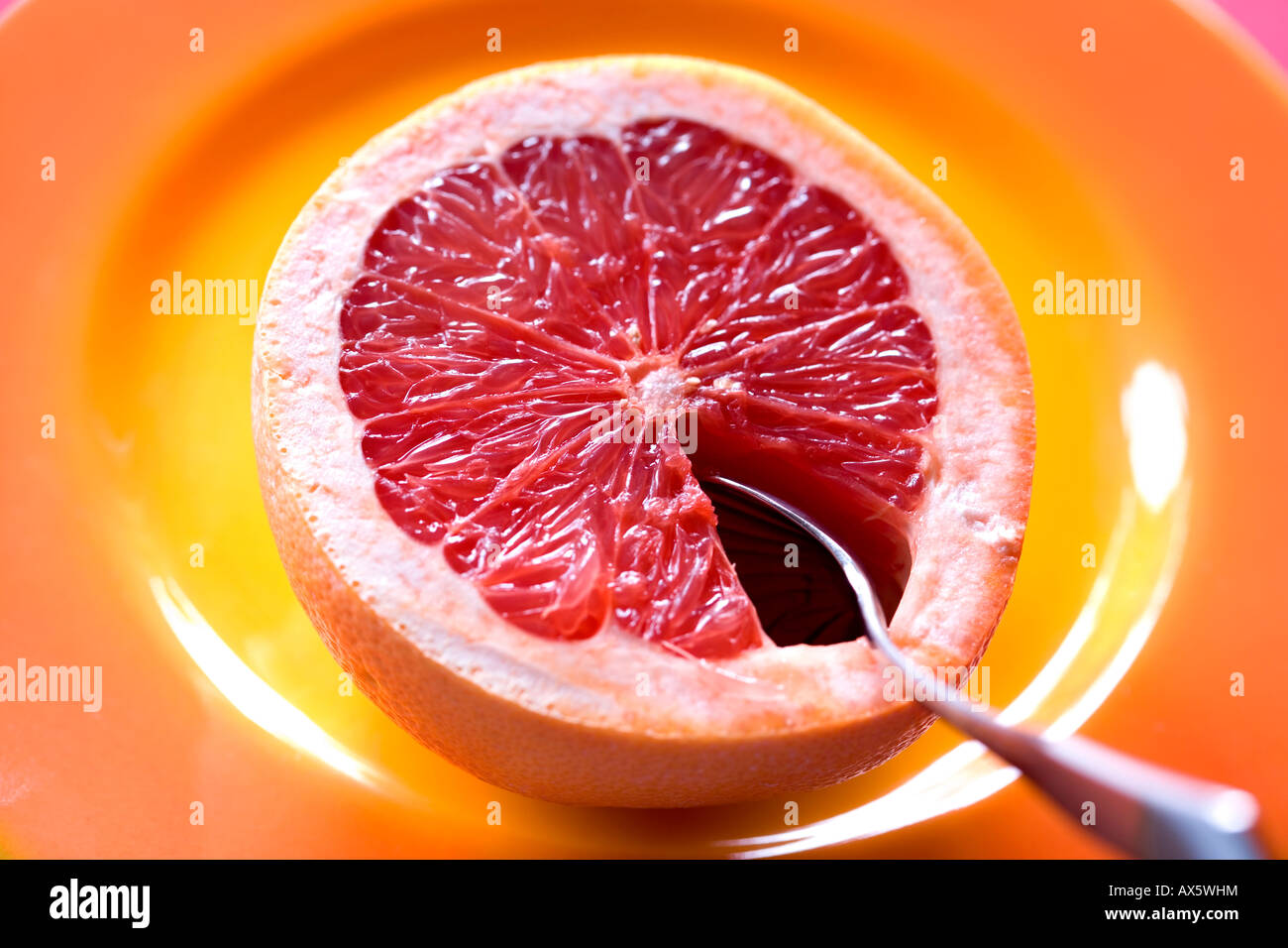 Halved grapefruit with spoon on a plate Stock Photo - Alamy