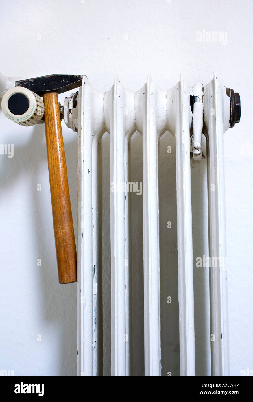 Old radiator, peeling paint and a hammer: symbolic picture for repair ...