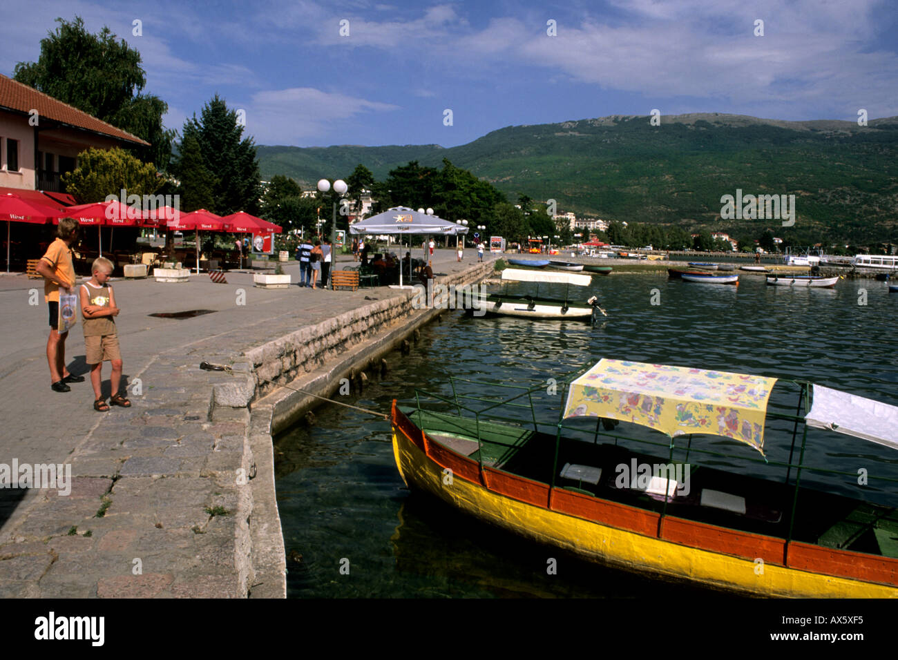 Locals looking at colorful boat on Lake Ohrid in holiday town of Ohrid ...
