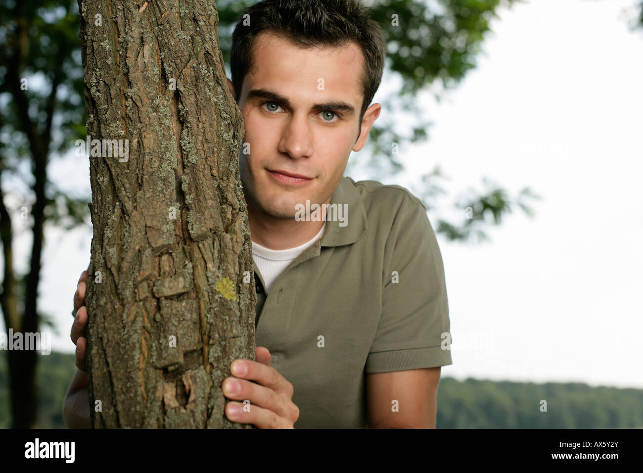Portrait of a mid adult man behind a tree Stock Photo - Alamy