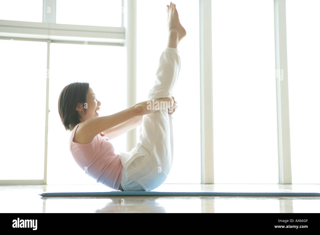 A young woman is elated as she holds her legs straight up in the air ...