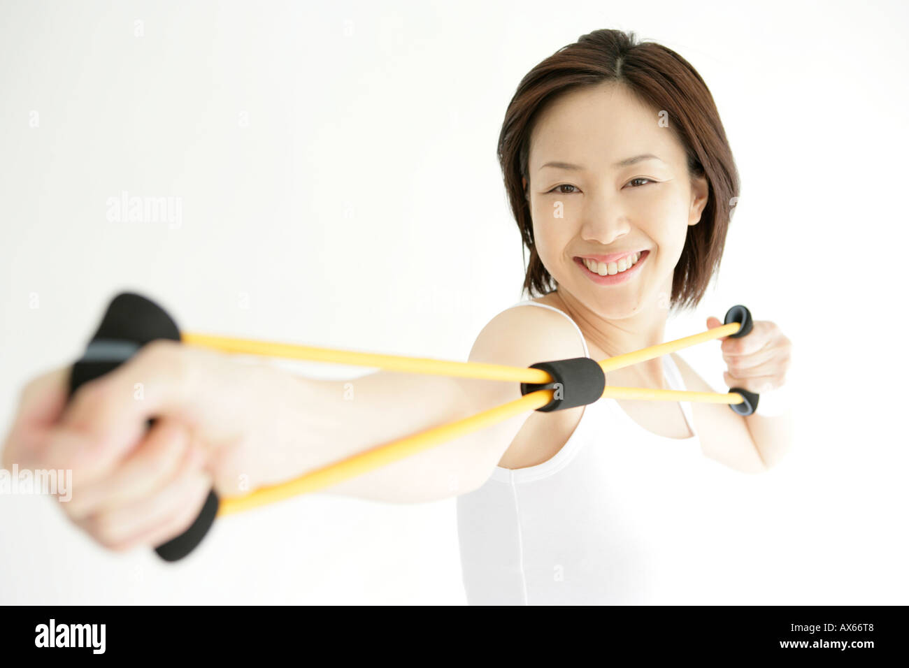 A young woman smiles as she uses the stretching rope for an exercise ...