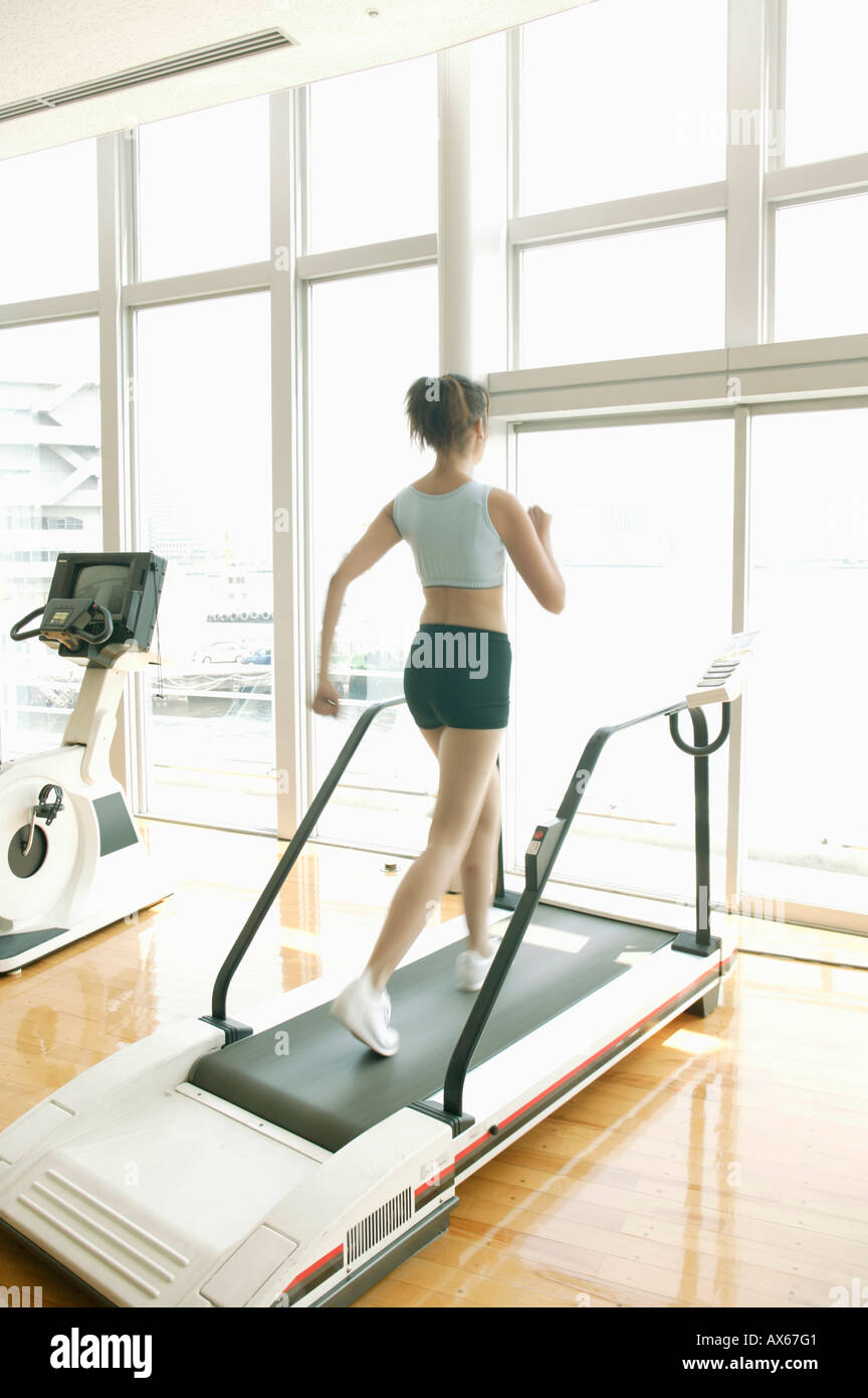 A young woman jogs on a walker as she exercises in a well equipped gym ...