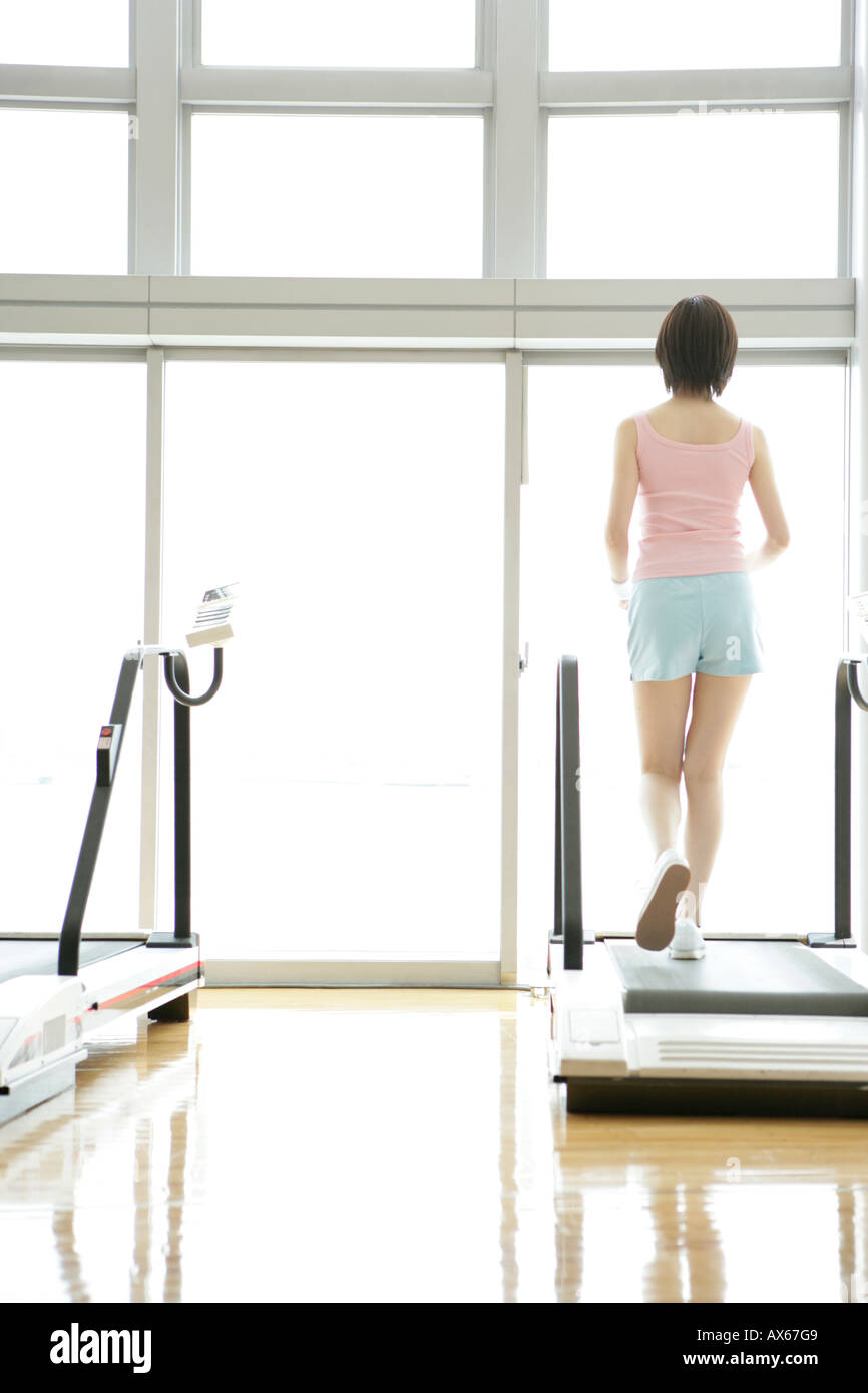 A young woman jogs on a walker as she exercises in a well equipped gym ...