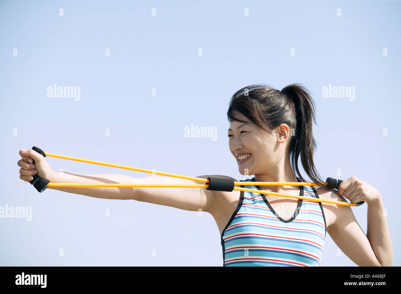 A woman working out as she stretches a rope tightly with her hands ...