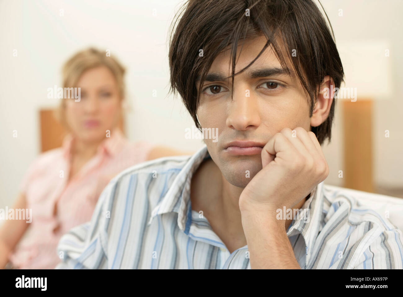 Dissatisfied young man, woman sitting in background Stock Photo - Alamy